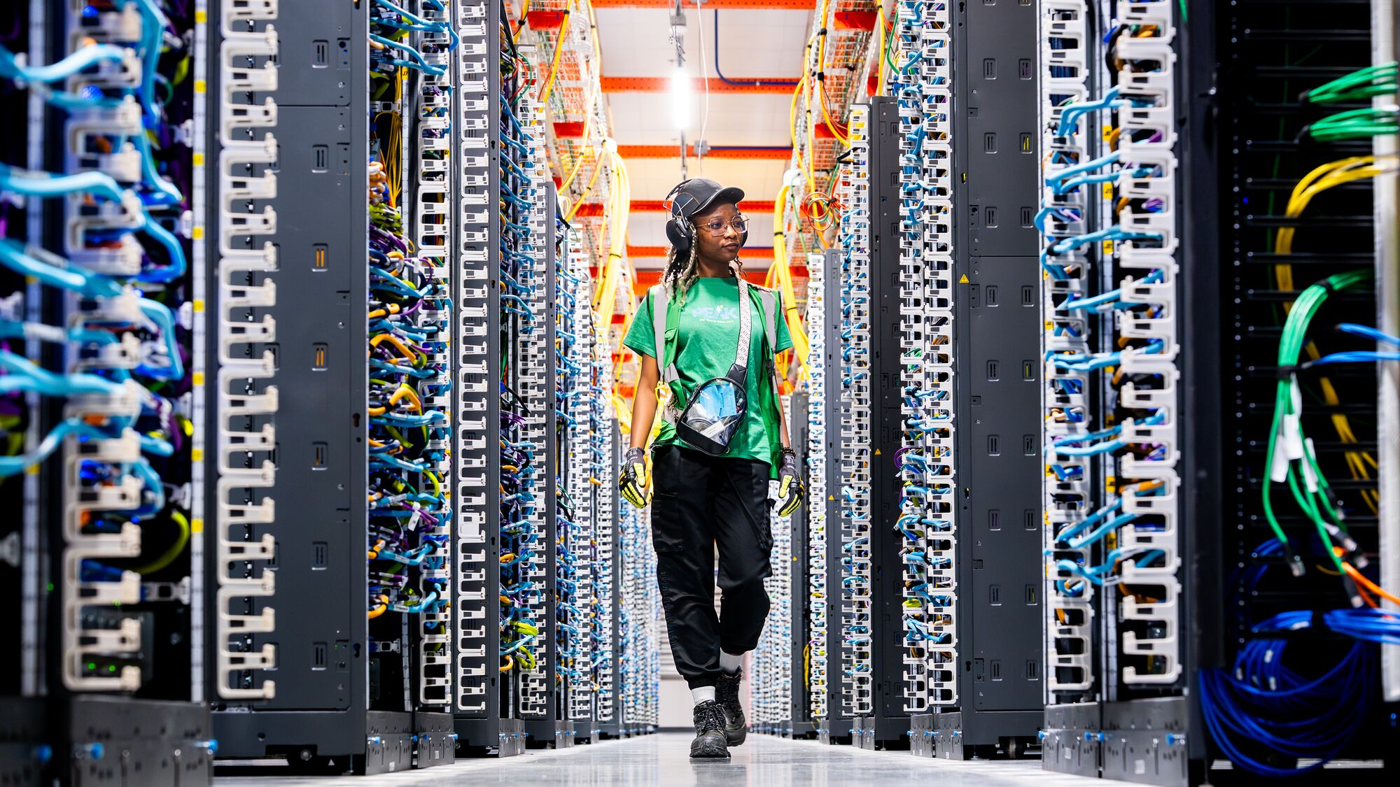 A data center technician walking between server racks inside Project ...